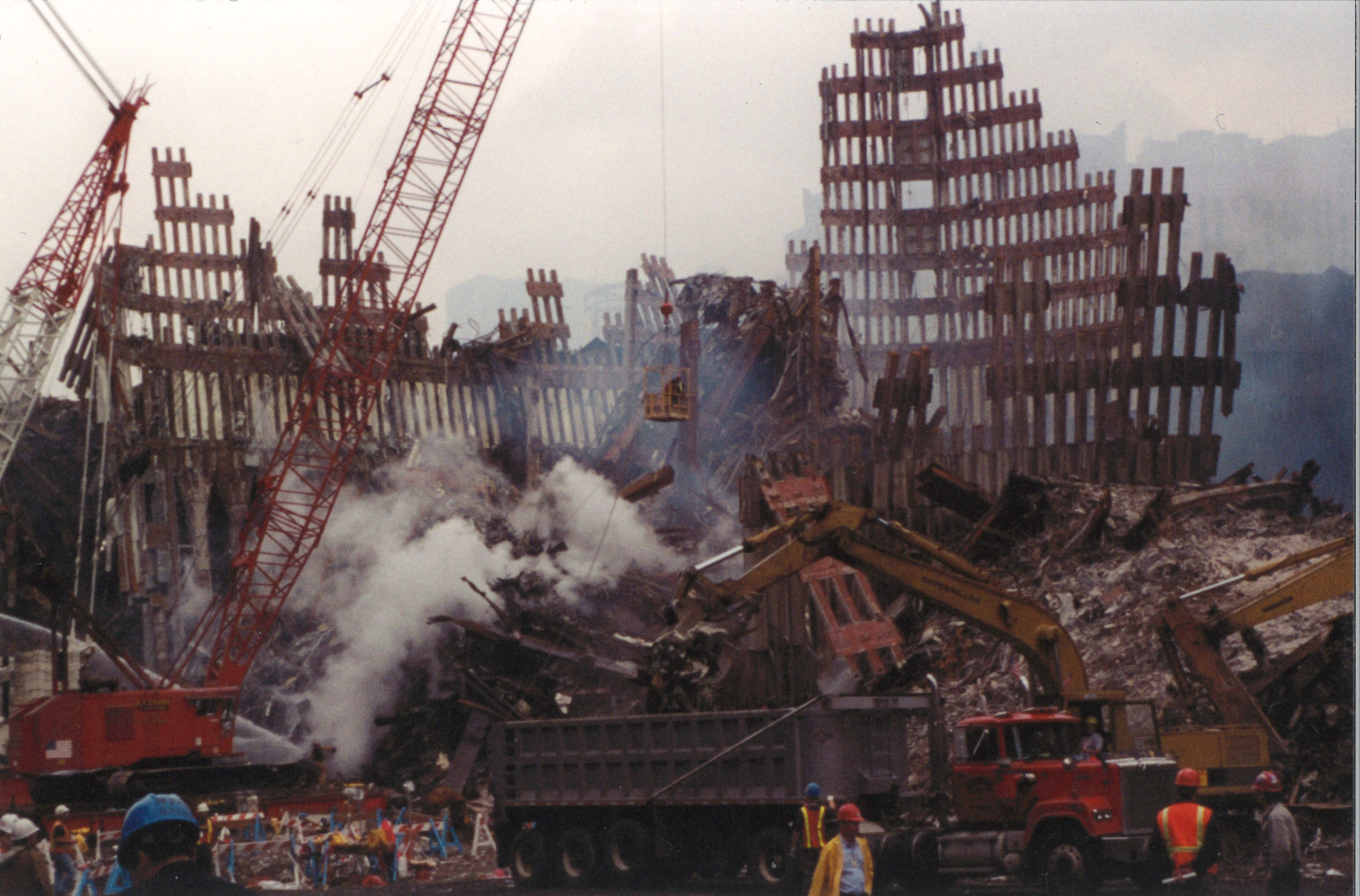 Diggers, cranes, dump trucks, and men working in the still-smoking ...
