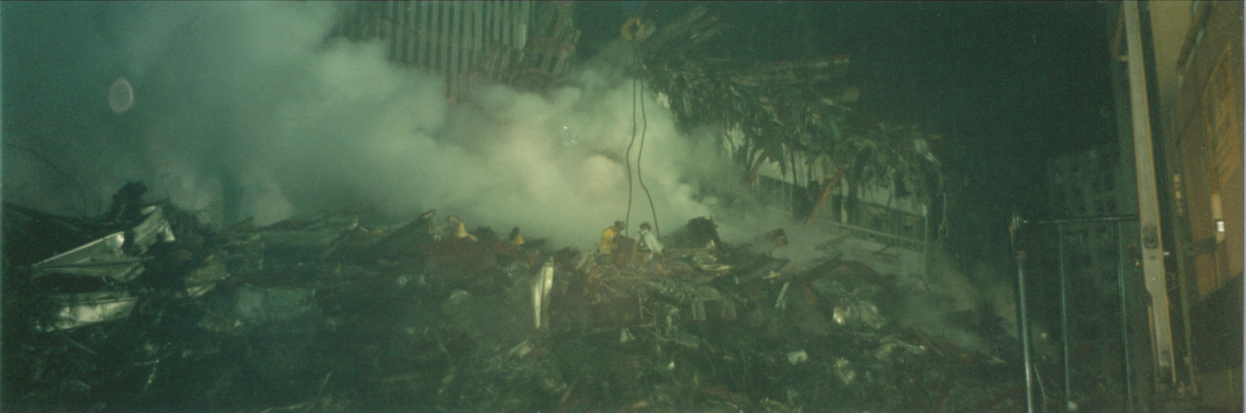 Smoke Pouring Over Rubble with Barely Visible Workers at Night ...