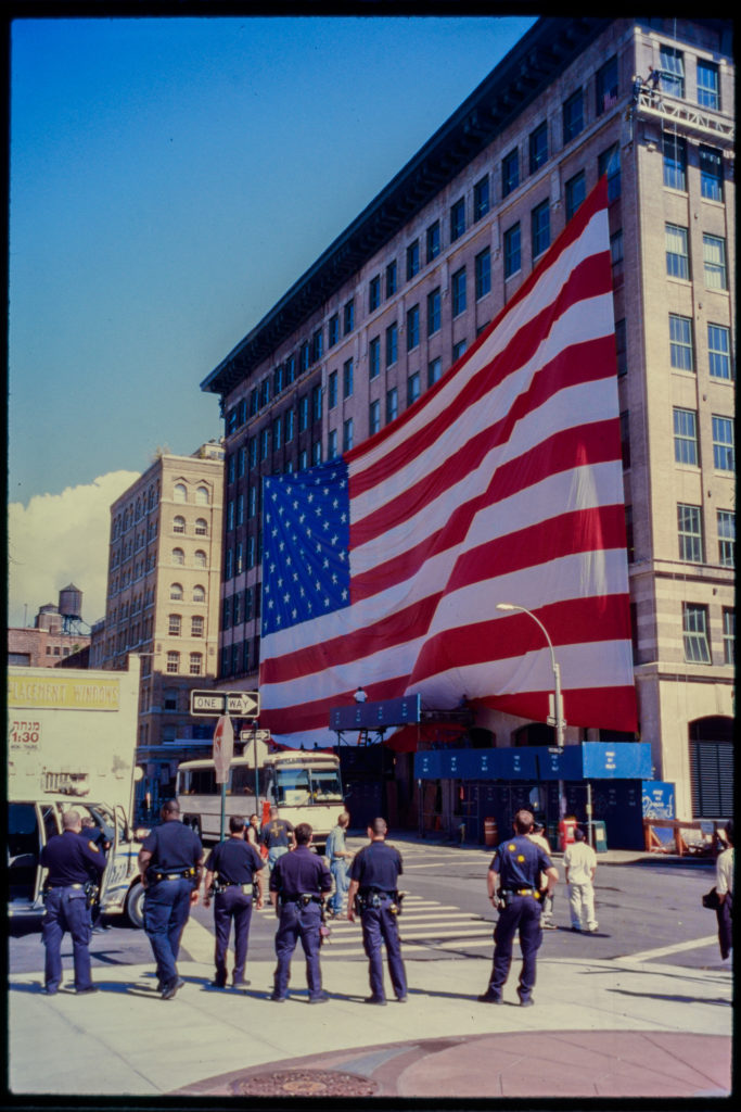 Six Police Officers Look Up at Enormous American Flag at Hubert and ...