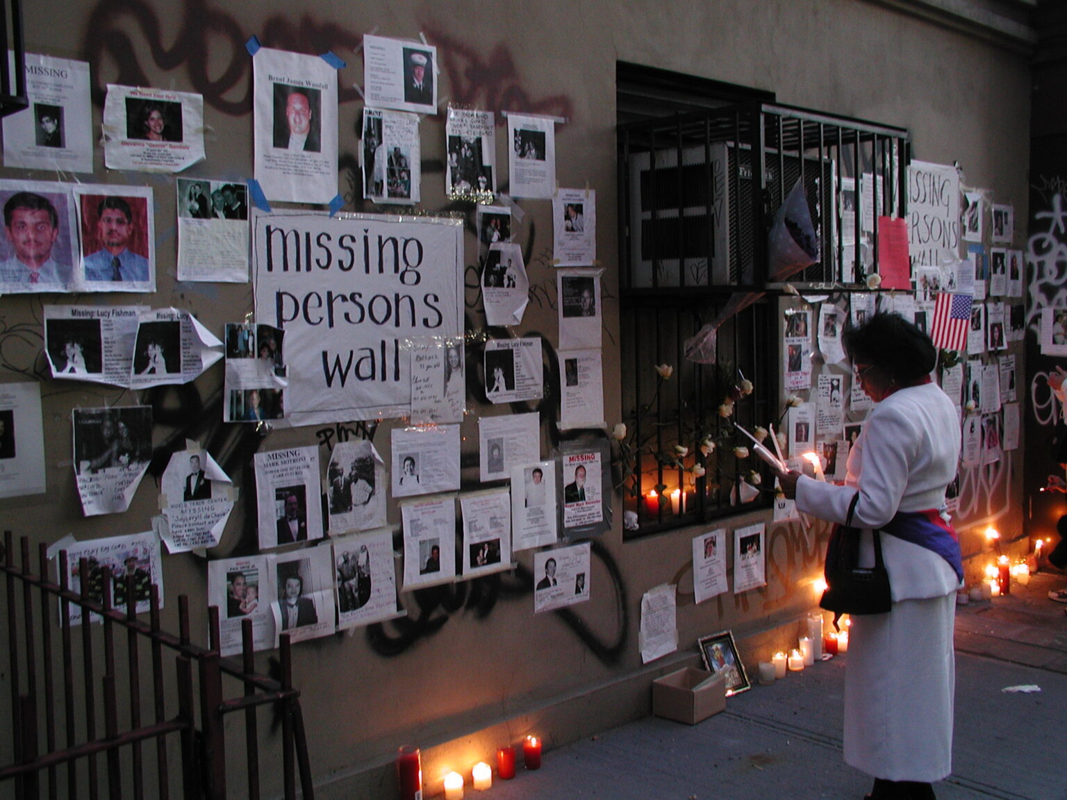 Woman looking at missing persons wall - Village Preservation